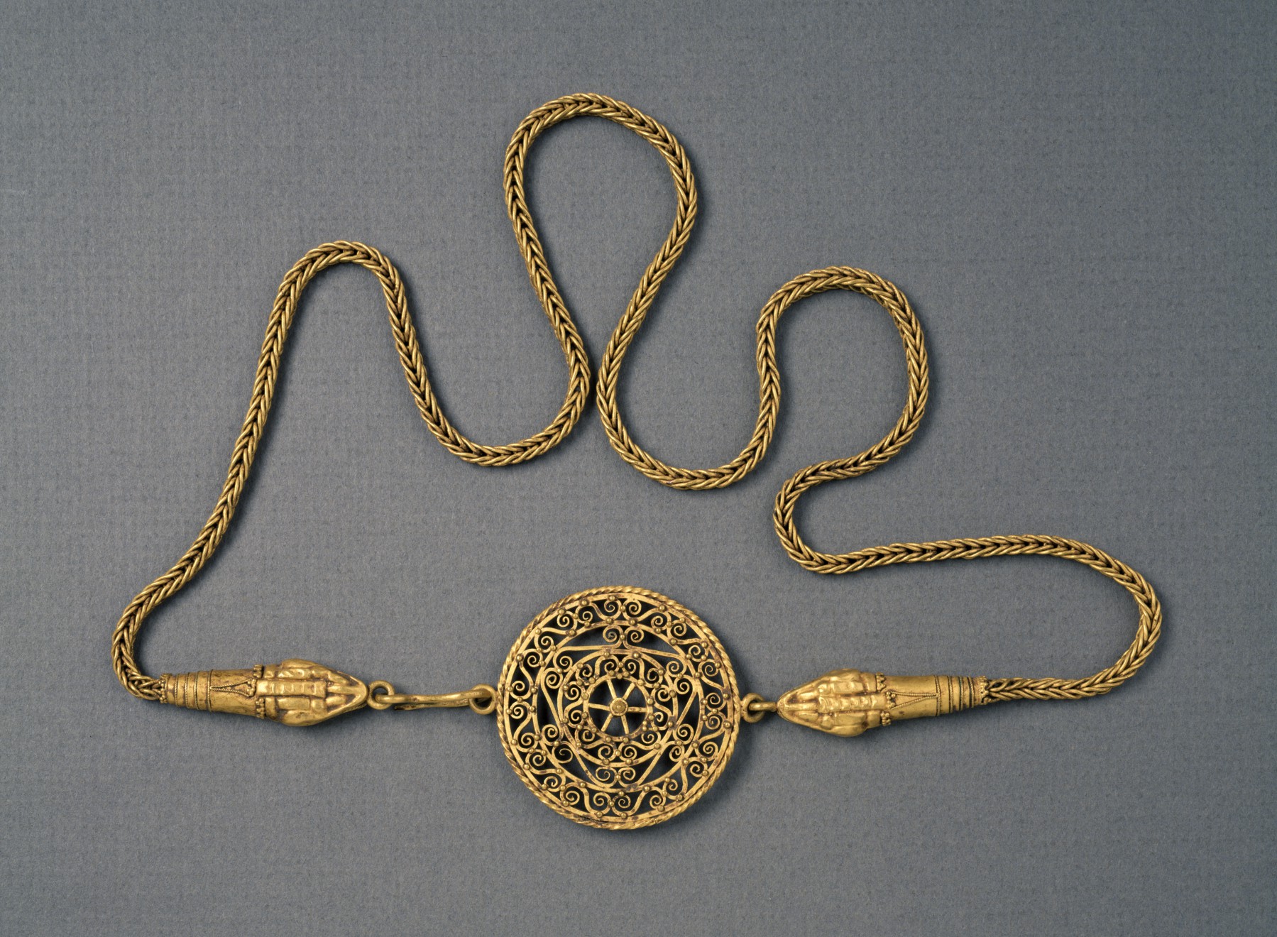 Roman necklace with a large disk and snake head clasp. The object is ...